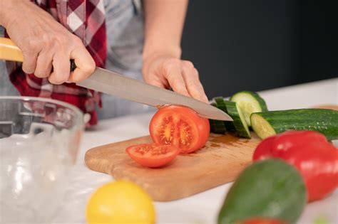 닫습니다 부엌에 서 가족 저녁 식사를 위해 야채 샐러드를 준비 보드에 토마토와 오이를 절단 하는 여자 건강한 음식 생활 건강한 라이프스타일 가정 주방에 대한 스톡 사진 및