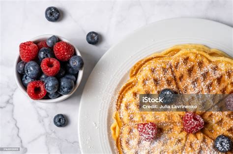 벨기에 와플과 대리석 배경에 라즈베리와 블루 베리의 혼합의 평면도 맛있는 여름 아침 식사 수제 둥근 와플과 딸기의 스택 플랫