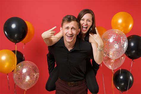 멋진 검은 옷 축 하 생일 크리스마스 파티 밝은 빨간색 배경에 공기 풍선에 고립 된 젊은 부부 세인트 발렌타인의 국제 여성의 날 행복 한 새 해 2019 개념 모의 2019