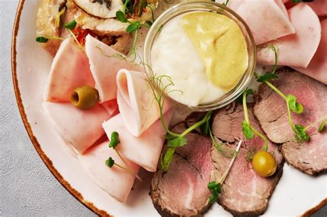 Premium Photo Slices Of Ham And Smoked Meat With Sauce And Olives