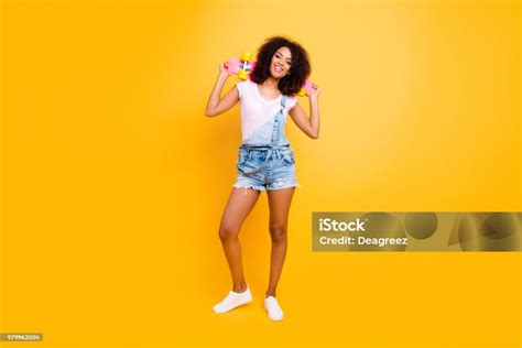 Fullbody 청바지 노란색 배경에 고립 된 어깨에 스케이트 보드를 들고 전체에 밝은 예쁜 여자의 초상화 극단적인 균형 개념