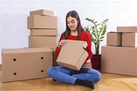 젊은 여자는 상자를 포장하고 새 아파트로 이사합니다 새로운 장소를 옮기는 젊은 여성과 수리 개념 바닥에 앉아 많은 판지 상자를 가진 행복한 젊은 여성 사진