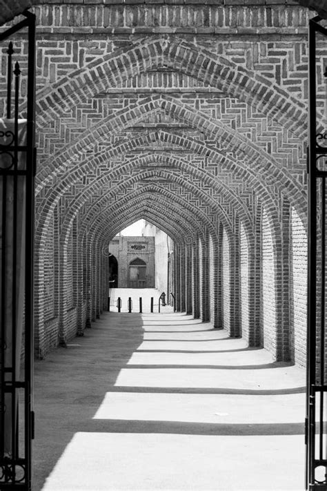 Two People Are Standing In An Arched Passageway With A Wall Behind Them