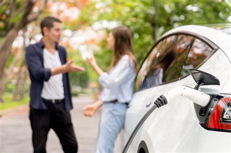 Lovely Young Couple Recharging Battery For Electric Car In Autumn