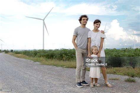풍력 터빈 농장의 행복한 가족 흐린 하늘을 배경으로 풍차공원에서 아빠와 엄마 딸이 함께 시간을 보낸다 부모와 함께 어린 소녀 아이 생태학 대체 재생 에너지 기술 3 명에