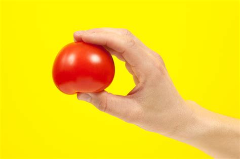 노란 배경에 고립 된 화려한 신선한 빨간 토마토를 들고 손을 요리하는 남자 신선한 맛있는 토마토를 보여주는 흰색 남성 손 건강한