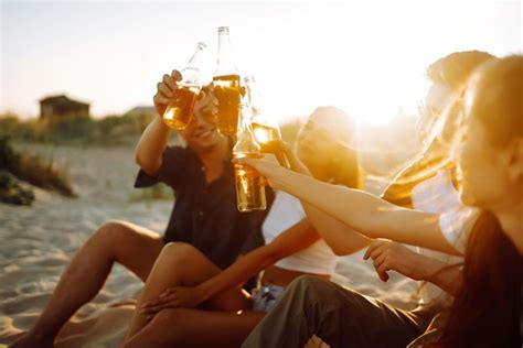 Premium Photo Young People Sitting Together At Beach Drinking Beer