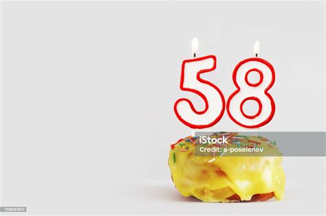 58 년 기념일 58 번호의 형태로 빨간색 테두리가 있는 흰색 불타는 촛불 생일 컵 케 익 복사 공간 밝은 회색 배경 0명에