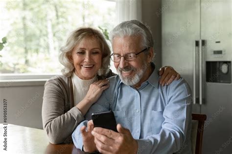 Using Gadget Together Curious Aged Wife Embrace Shoulders Of Beloved