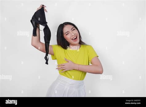 Surprised Young Asian Woman In Yellow Shirt Is Holding A Black Bra For