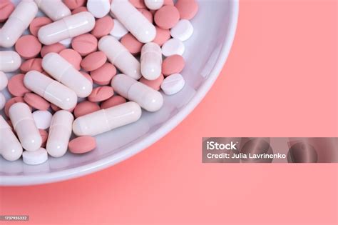 분홍색과 흰색 알약과 캡슐로 가득 찬 접시가 있는 분홍색 배경 치료 호르몬 피임약 또는 체중 감량 알약이 포함된 다이어트 텍스트