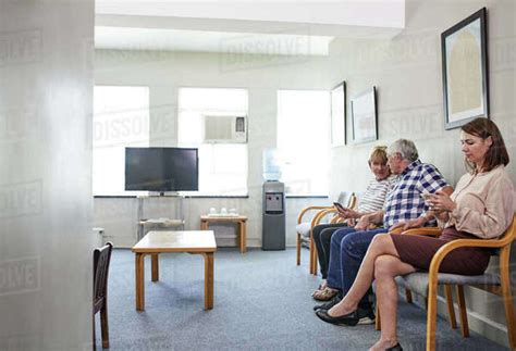 Patients Waiting Using Smart Phones In Clinic Waiting Room Royalty