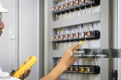 남성 전기 기술자가 배전반 인 전기 터미널 상자에서 일합니다 자기 접촉기 및 과부하 릴레이가있는 제어판 주 배전 보드의 전압 측정 전기 연료 및 전력 생산에 대한 스톡 사진