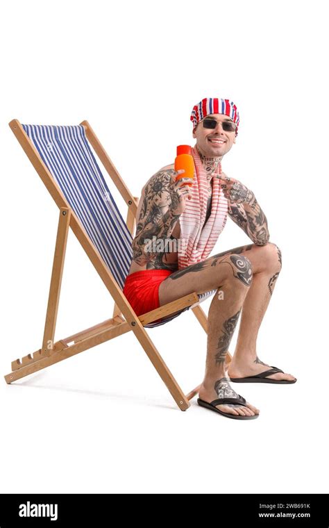 Tattooed Man With Sunscreen Cream Sitting On Deck Chair Against White