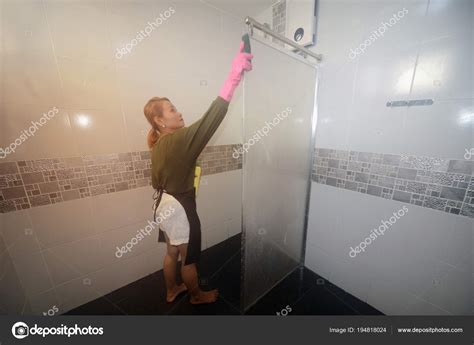 Asian Female Maid Or Housekeeper Cleaning On Toilet Partitions In