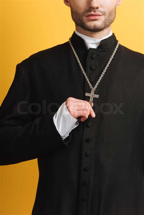 Partial View Of Catholic Priest Touching Cross On His Necklace Isolated On Yellow Stock Image