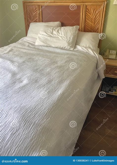 Unmade Bed In A Hotel Room With Two White Pillows And A White Duvet