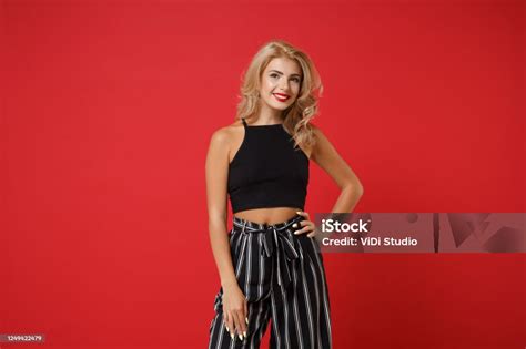 밝은 빨간 벽 배경 스튜디오 초상화에 고립 포즈 검은 옷을 입고 아름다운 미소 예쁜 젊은 여자 소녀 사람들은 진지한 감정 라이프 스타일 개념 복사 공간을 모의합니다 카메라를