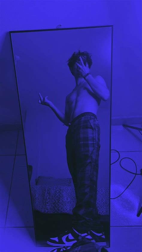 A Man Standing In Front Of A Mirror Talking On A Cell Phone