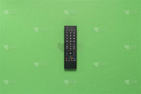 绿色背景上的黑色遥控器。电视、电影、电视节目、体育的概念。平面布局 顶部视图