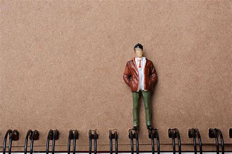 A Small Statue Beside A Spiral Notebook Businessman Paper Doll Photo
