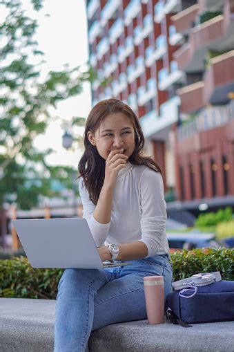 귀여운 젊은 아시아 여학생은 야외에서 노트북 컴퓨터에서 일하고 개념을 공부하고 공개 도메인에서 일합니다 Outside Lands