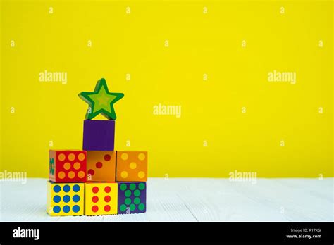 Square Block Puzzle Toy On Table With Yellow Wall Background Stock