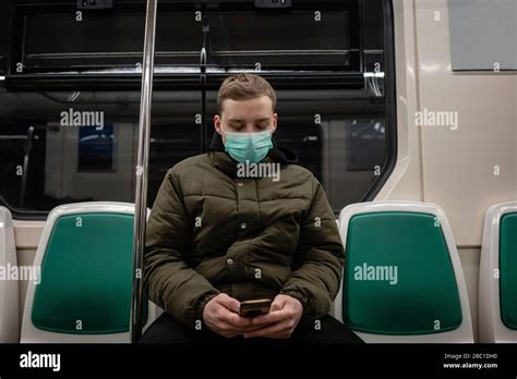 Young Man In Commuter Train Wearing Face Mask Using Smartphone Stock