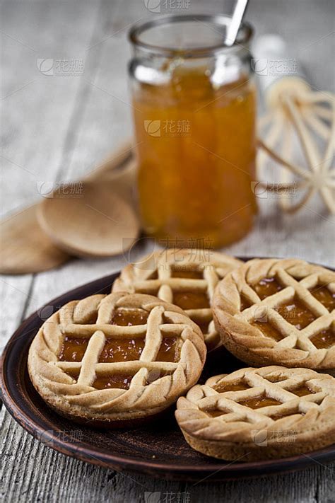 陶瓷盘子和厨房烘焙用具上的新鲜烤果馅饼馅料是果酱或杏子果酱放在质朴的木桌上