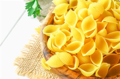 나무 테이블에 Conchiglie 파스타로 요리 배경입니다 파 슬 리와 나무 그릇에 Cockleshells의 형태로 파스타 건조