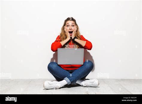 Portrait Of An Excited Young Woman Wearing Hoodie Sitting Isolated Over