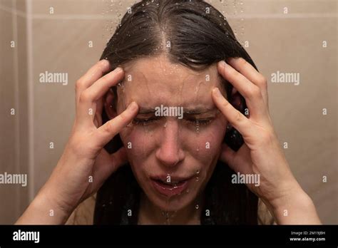 Young Woman In Shower With Water Running Down Her Face Holding Her