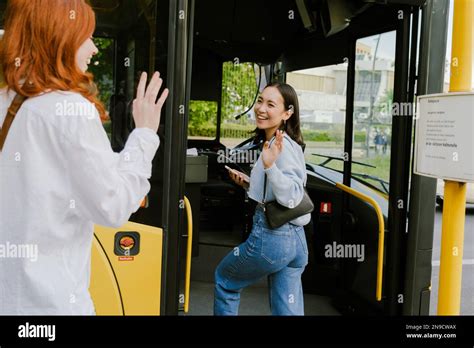 Redhead Girl Waving To Her Cute Smiling Asian Friend Who Boarding Bus