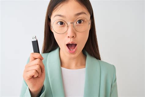 고립 된 흰색 배경 위에 Usb 메모리를 들고 젊은 중국 사업가는 깜짝 얼굴로 충격에 무서워 두려움과 두려움 표정으로 흥분