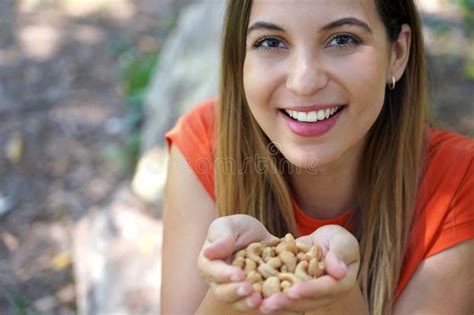 Beautiful Healthy Girl Showing Cashew Nuts In Her Hands Outdoors Looks