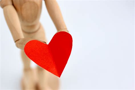 회색 배경에 나무 마네킹의 손에 빨간 종이 심장 발렌타인 데이 사랑 진정한 느낌의 트렌디 한 미니멀 한 개념 공간을 복사합니다