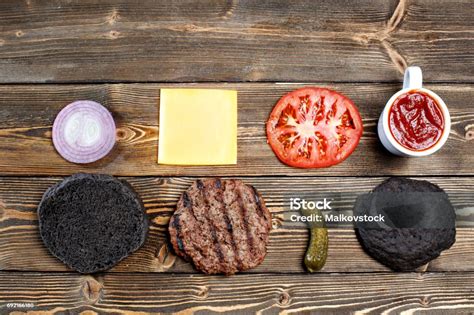 블랙 버거 요리 재료입니다 구운된 고기 패티 빵 양파 토마토 양상추 피 클 소스 검은 나무 배경 평면도 위에 치즈 쓰레기에 대한