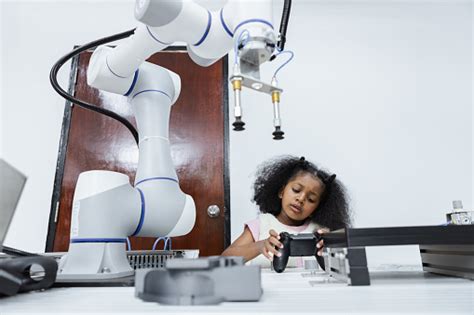 조이스틱을 사용하는 어린이 소녀 아프리카계 미국인과 교실에서 스마트 로봇 팔을 제어하는 소녀 아프리카계 미국인 전기 시스템 기술 훈련 로봇 학습 혁신 Stem 교육