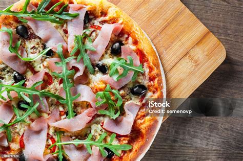 모 짜 렐 라 치즈 햄 후추 올리브 고기 토마토 소스 향신료와 신선한 Arugula 피자 나무 바탕에 이탈리아 피자 건강에 좋지