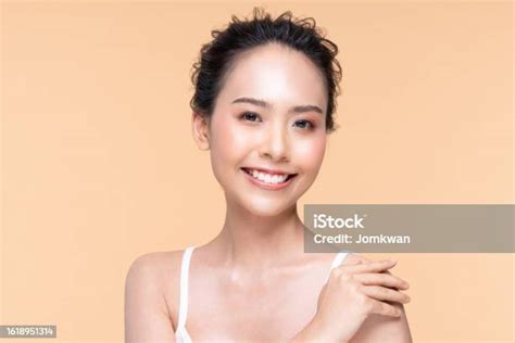 아름다운 아시아 젊은 여자 감동 부드러운 뺨 미소 와 깨끗 한 신선한 피부 행복과 쾌활 한 감정 베이지 배경에 고립 된 뷰티