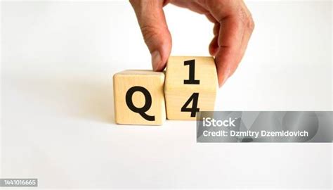 4 분기부터 1 분기까지의 상징 사업가는 나무 큐브를 돌리고 Q4라는 단어를 Q1로 바꿉니다 아름 다운 흰색 테이블 흰색
