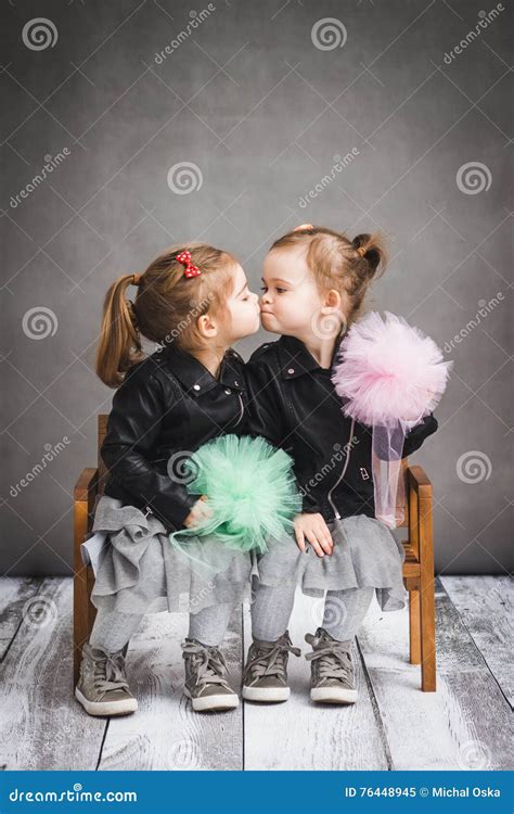 Deux Soeurs S Asseyant Sur Un Banc Et Se Donnent Un Baiser Image Stock