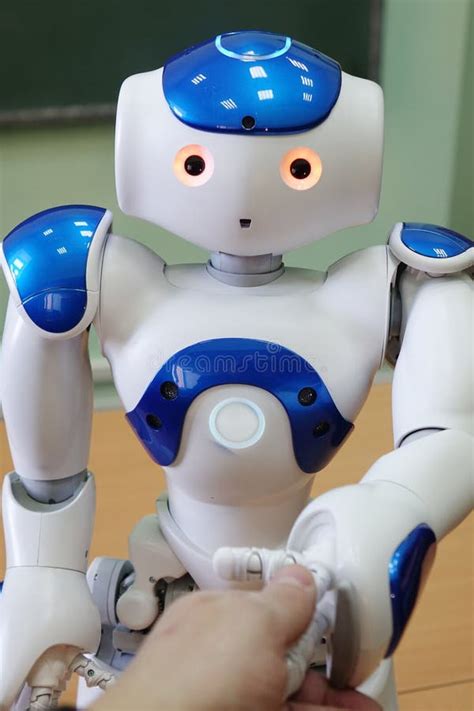 A Small Robot With A Human Face And A Humanoid Body Blue And White