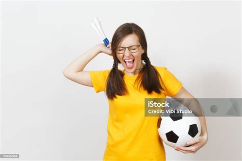 유럽 여자를 웃 고 두 재미 조랑말 꼬리 축구 팬 이나 안경 노란 유니폼 보류 축구 파이프 흰색 배경에 고립 된 공에 선수