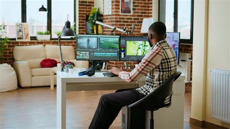 male video creator edits a multimedia project at a modern office stock