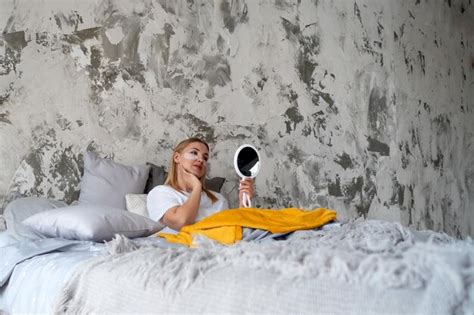 Premium Photo Young Woman Admires Herself In Mirror While In Bed