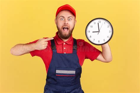 Surprised Man Worker Pointing At Big Wall Clock In His Hands Looking
