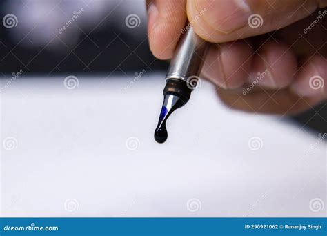 Drop Of Blue Ink Dripping Out From A Fountain Pen Nib Over White Paper