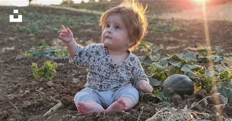 흰색과 검은색 꽃무늬 셔츠와 파란색 데님 반바지를 입은 소녀가 낮에 바닥에 앉아 있다 사진 Unsplash의 무료 배경 이미지