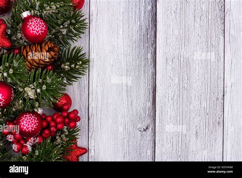 Red Christmas Ornaments And Branches Side Border On A Rustic White Wood Background Stock Photo